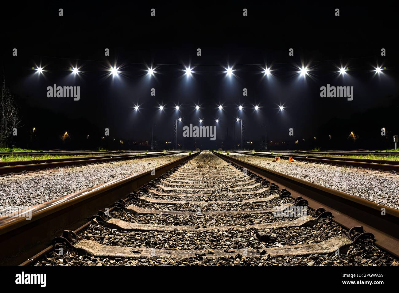 A dramatic nighttime landscape featuring a set of illuminated railway ...