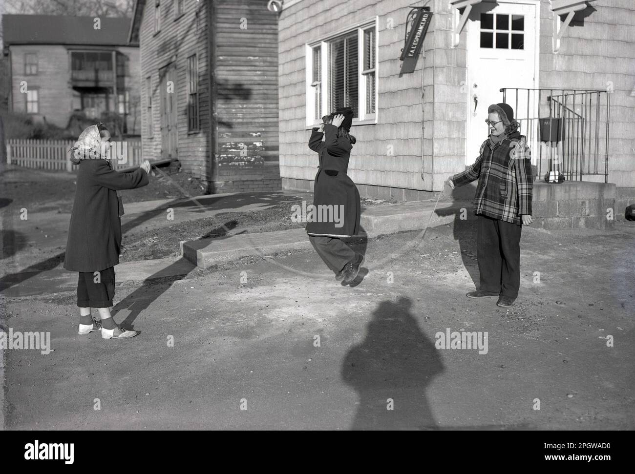 1950s, historical, outside, three girls in coats, playing a game of ...