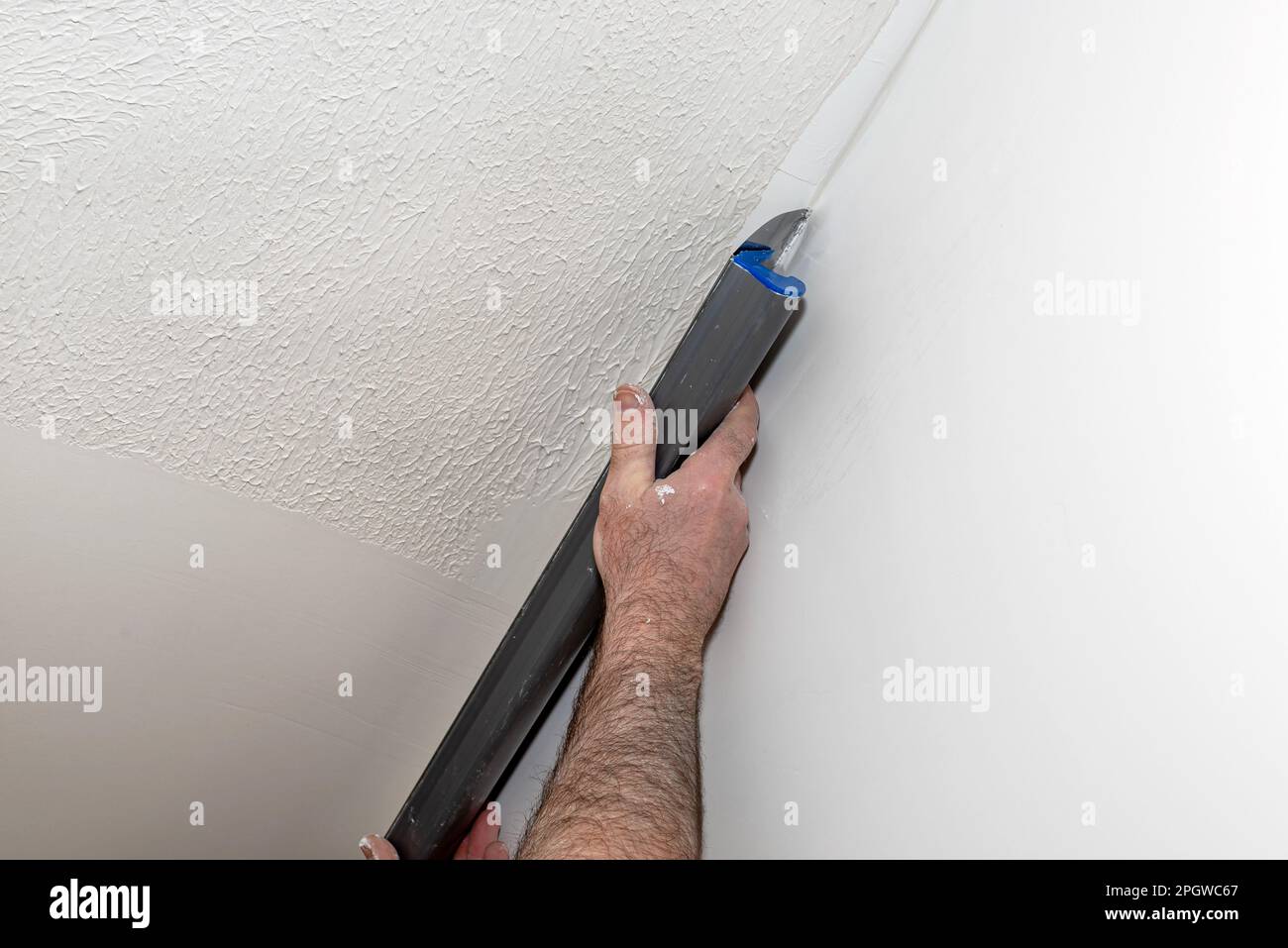A man applies ready-made polymer plaster from a bucket using special ...