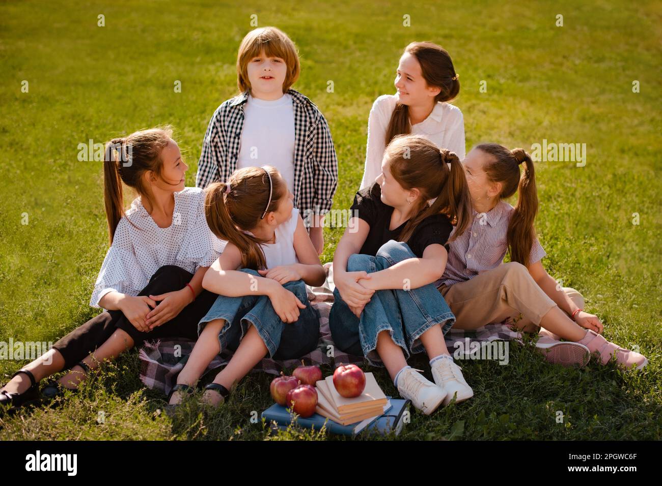 children boy and girls sitting on green grass in park. boy tell poem ...