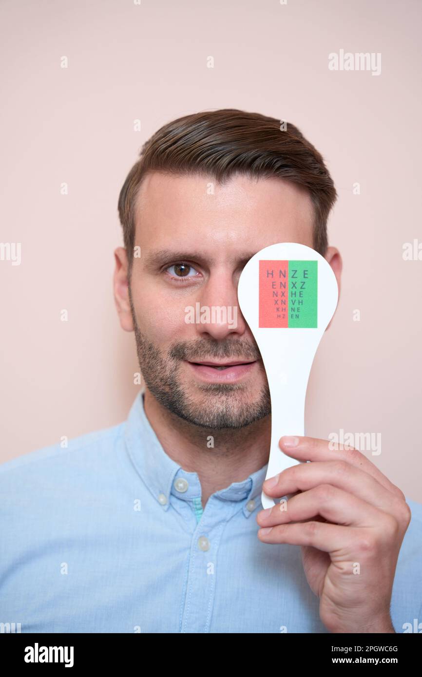 Positive man during checking eyesight in the isolated on light pink ...