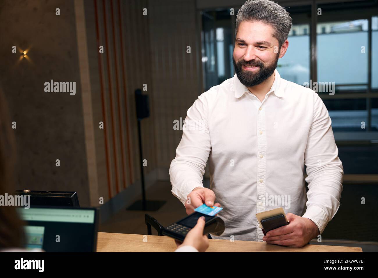 Joyful entrepreneur paying for hotel room at reception desk Stock Photo ...