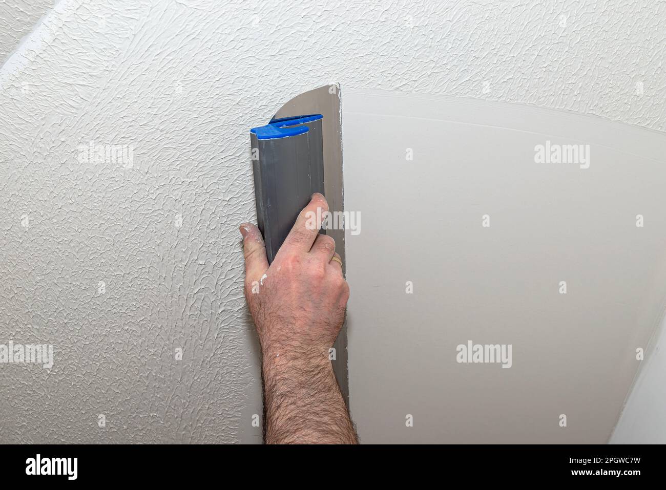 A man applies ready-made polymer plaster from a bucket using special ...