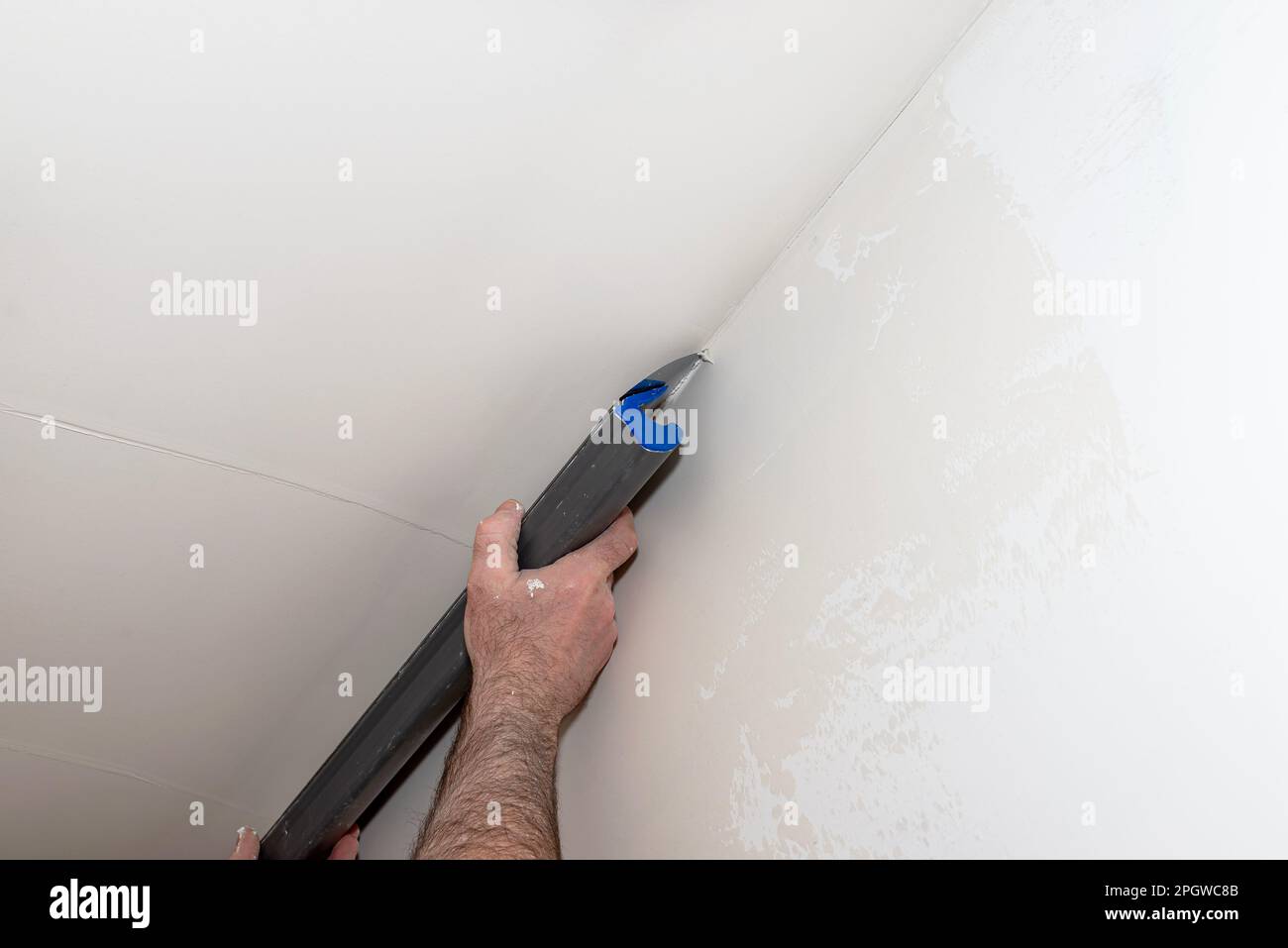 A man applies ready-made polymer plaster from a bucket using special ...