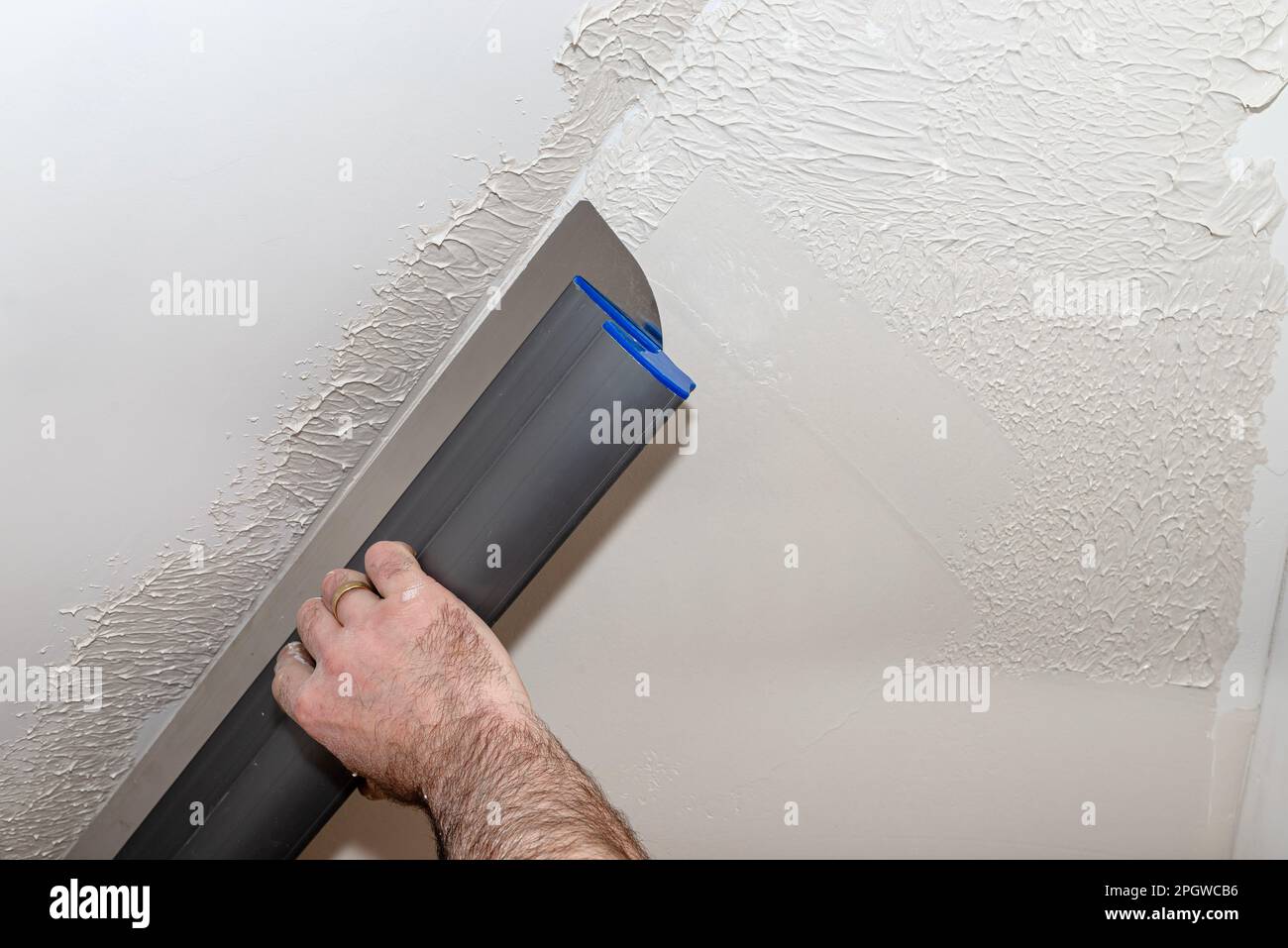 A man applies ready-made polymer plaster from a bucket using special ...