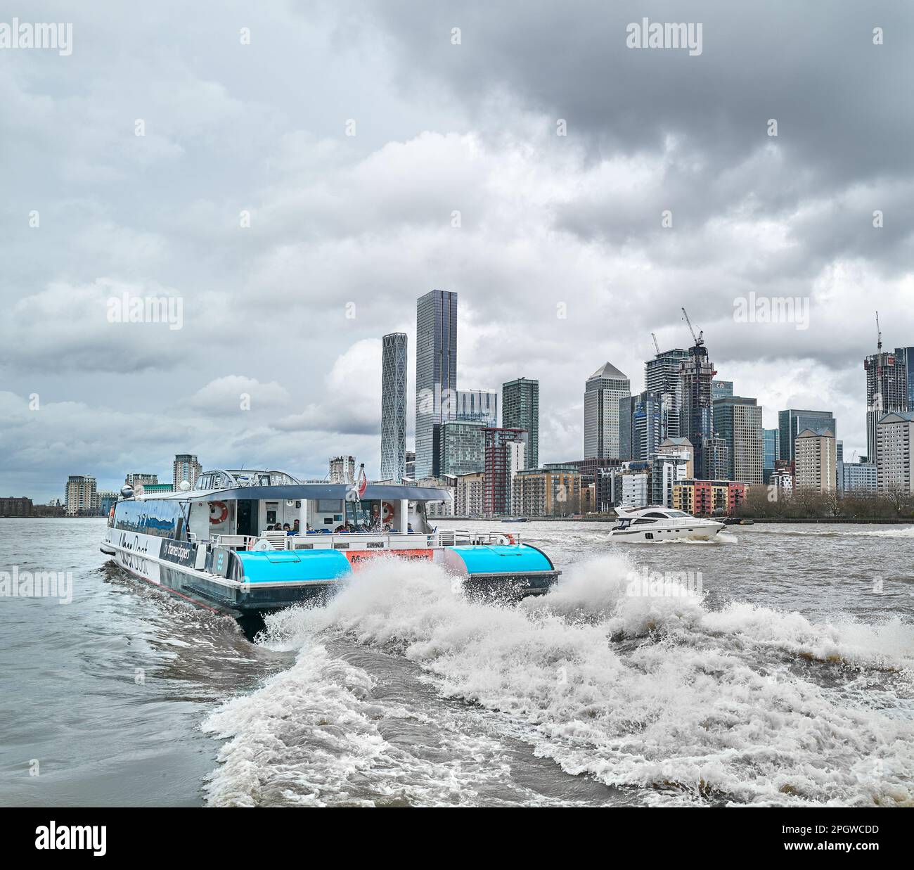An Uber Thames Clipper ferry boat accelerates towards Canary Wharf, one ...