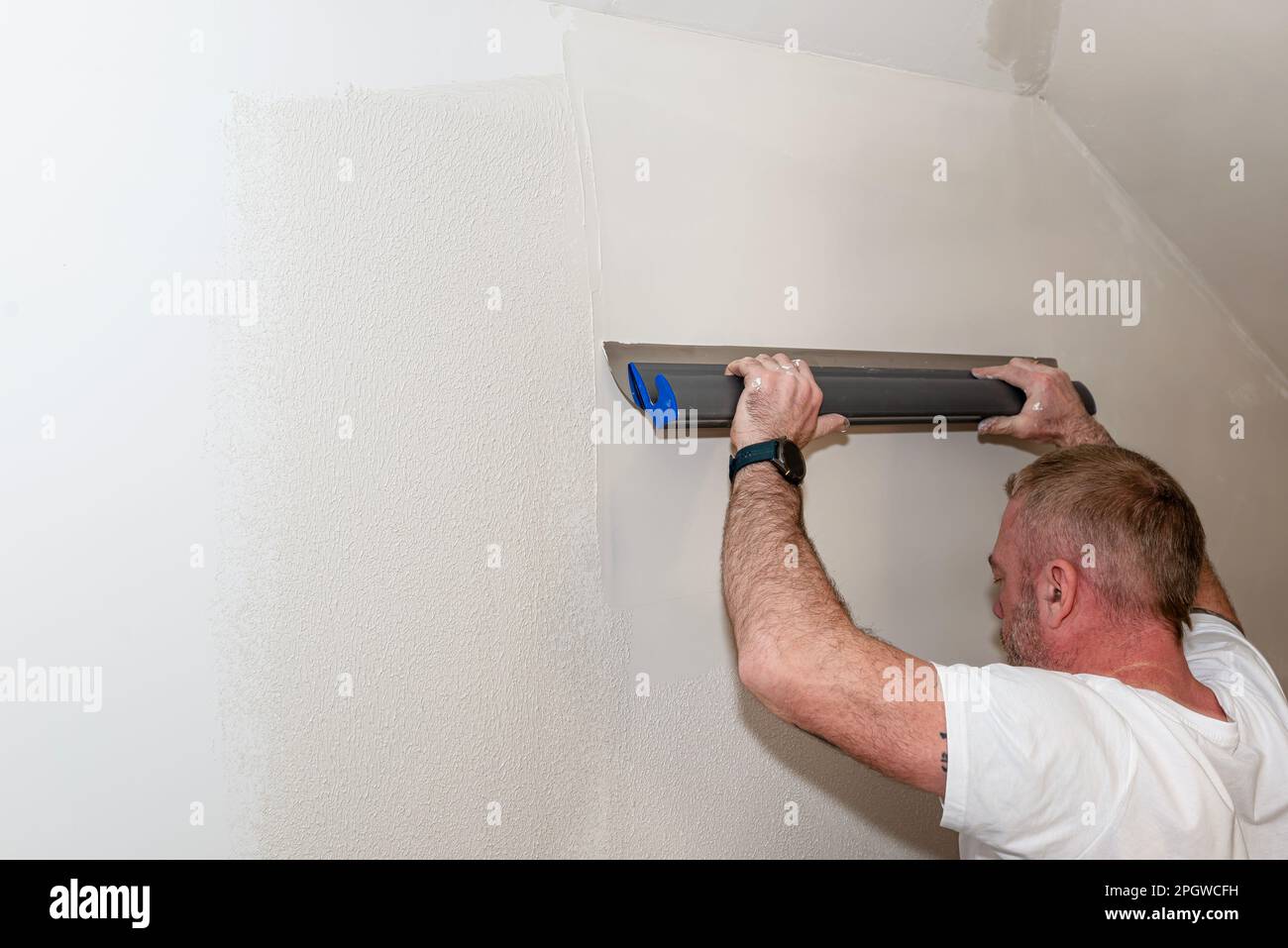 A man applies ready-made polymer plaster from a bucket using special ...