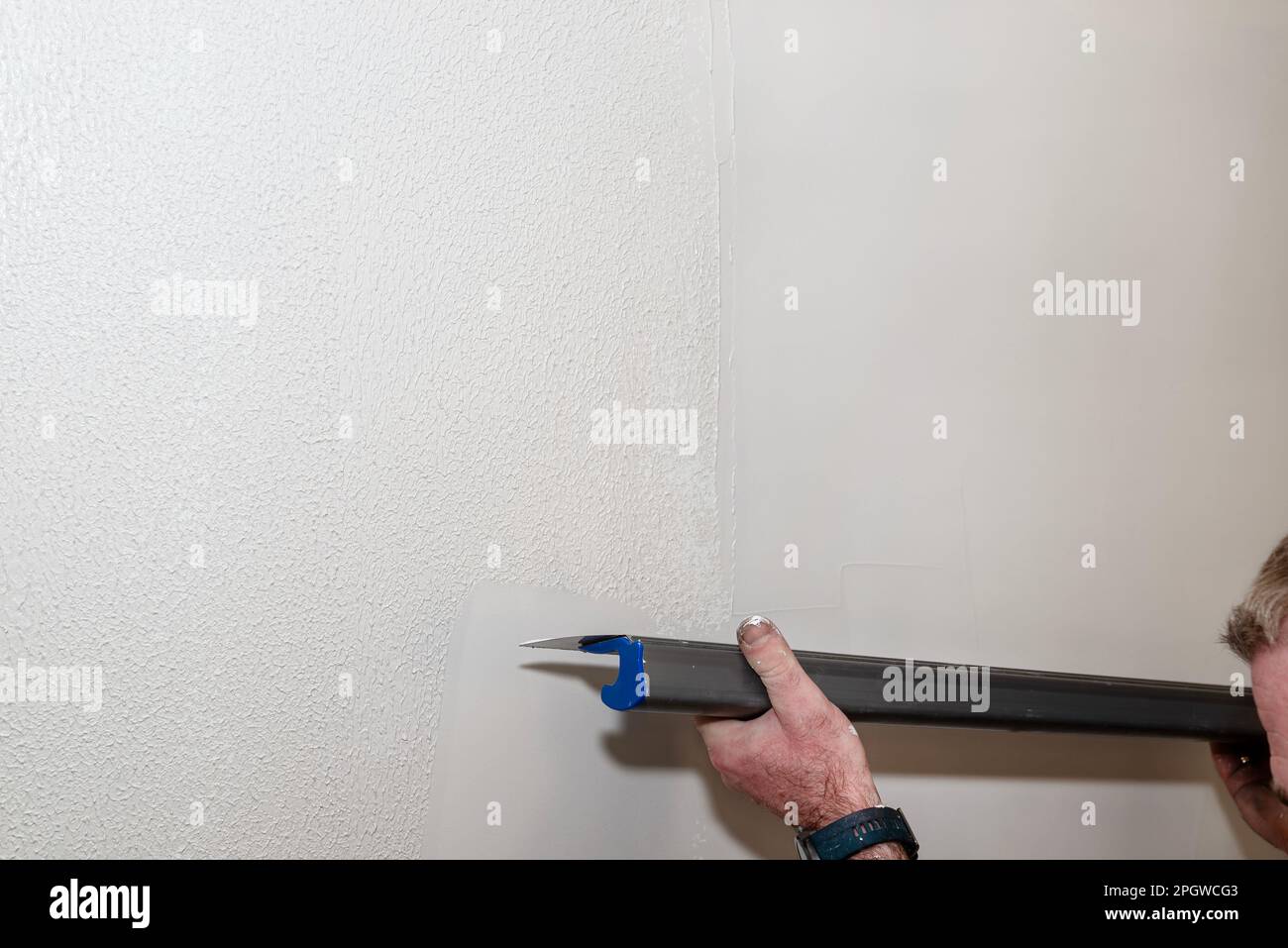 A man applies ready-made polymer plaster from a bucket using special ...
