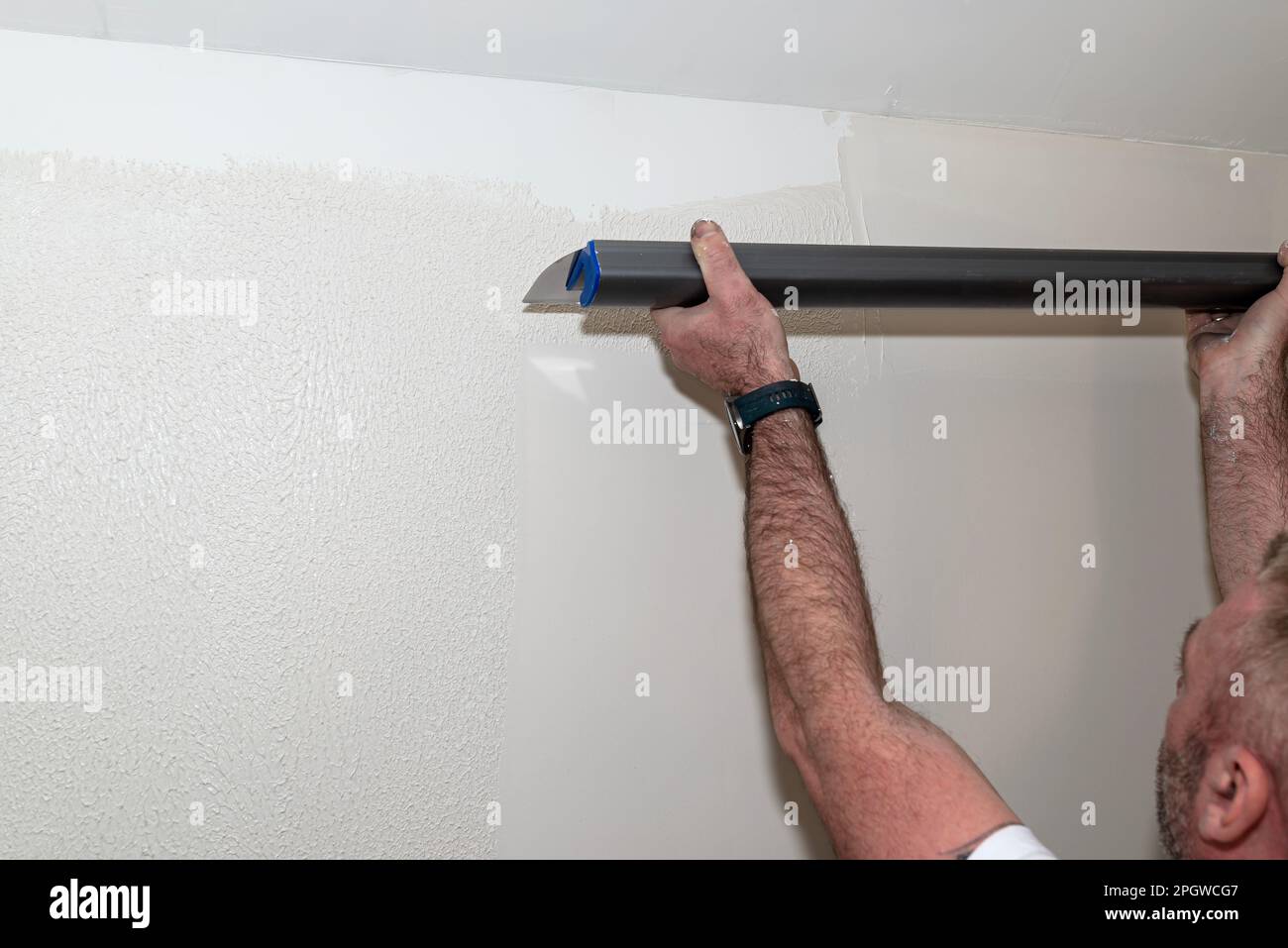 A man applies ready-made polymer plaster from a bucket using special ...