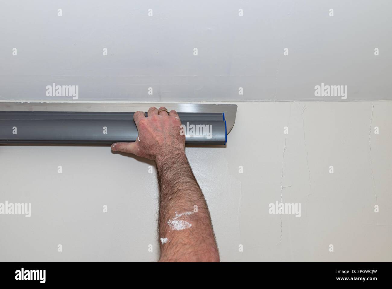 A man applies ready-made polymer plaster from a bucket using special ...