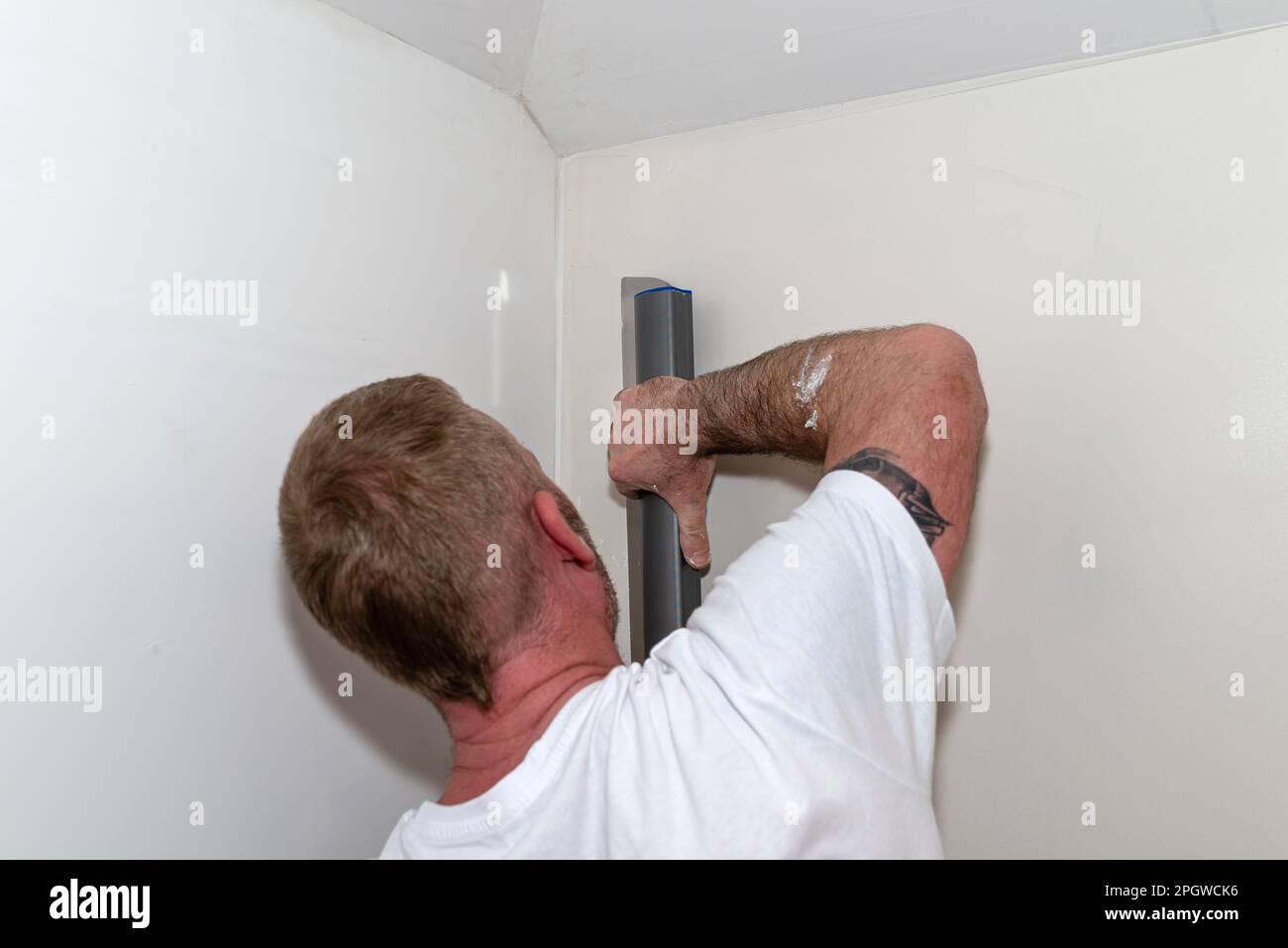 A man applies ready-made polymer plaster from a bucket using special ...