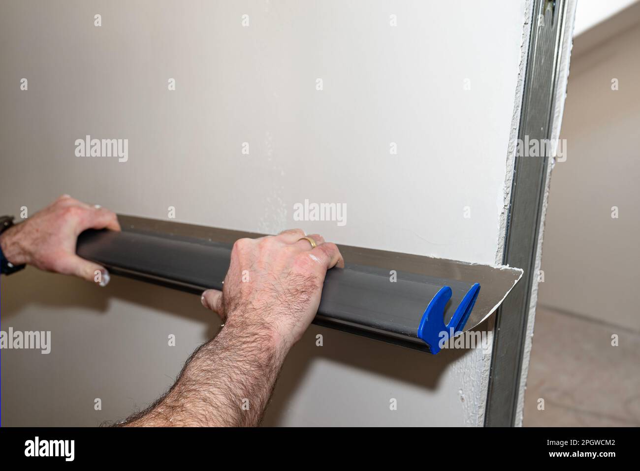 A man applies ready-made polymer plaster from a bucket using special ...