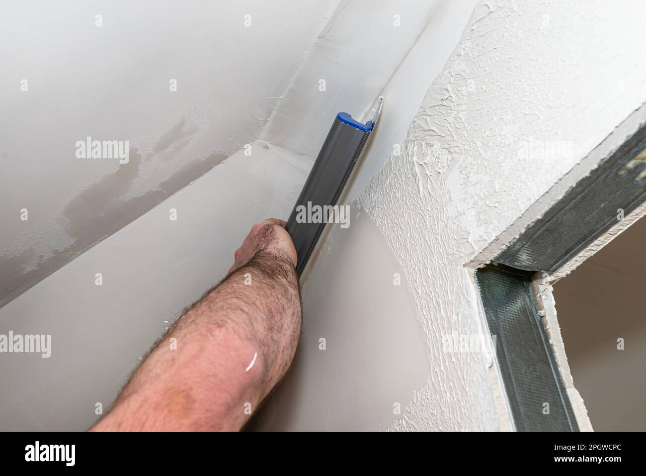 A man applies ready-made polymer plaster from a bucket using special ...