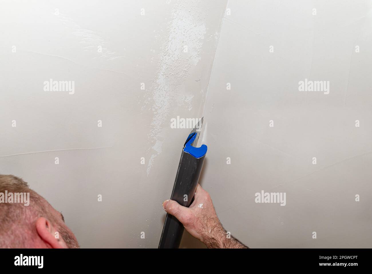 A man applies ready-made polymer plaster from a bucket using special ...