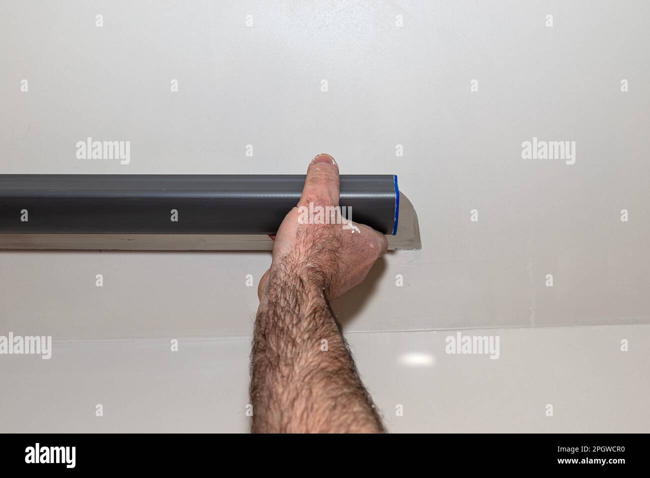 A man applies ready-made polymer plaster from a bucket using special ...