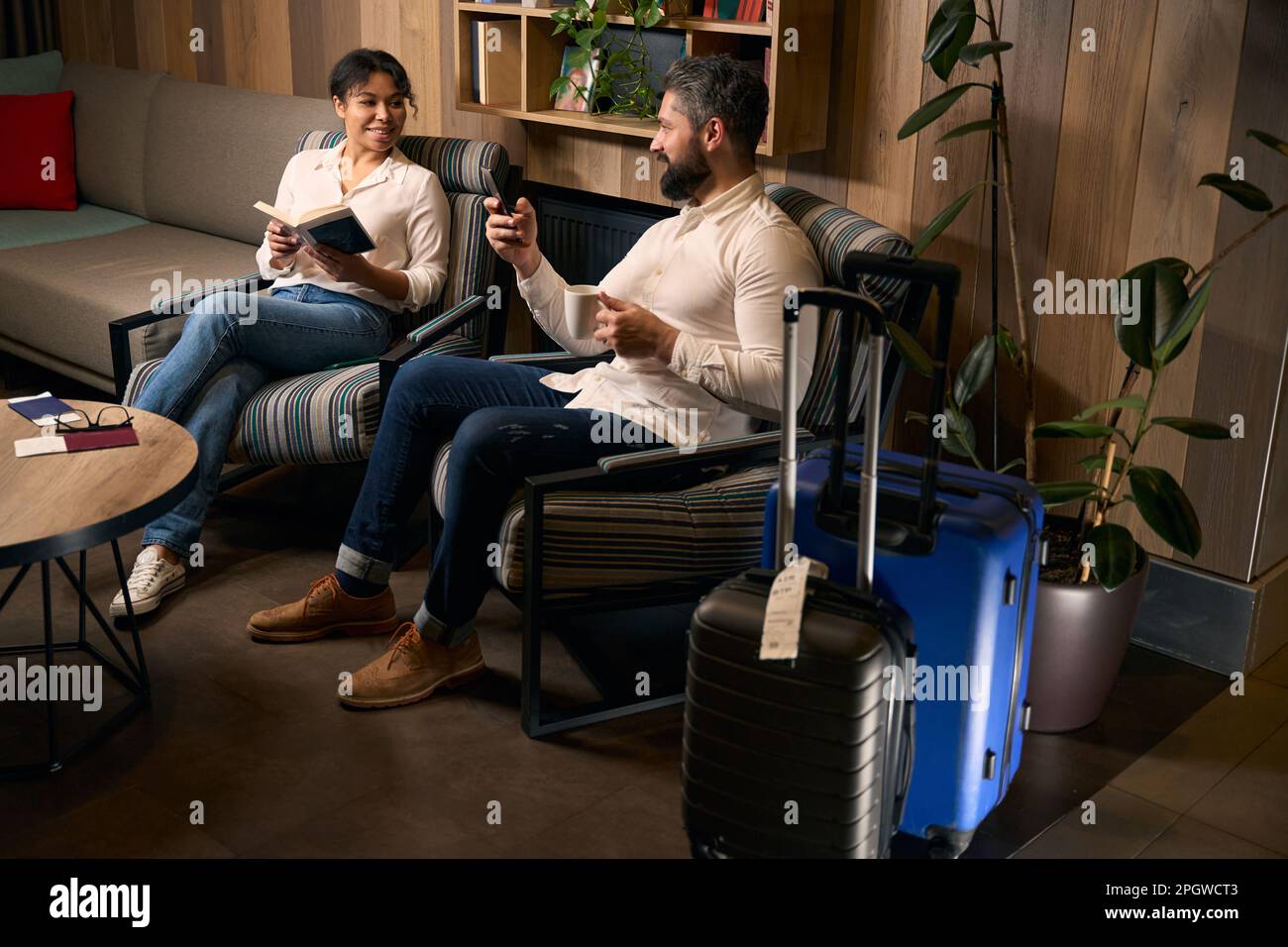 Tourist couple waiting for check-in in hotel foyer Stock Photo - Alamy
