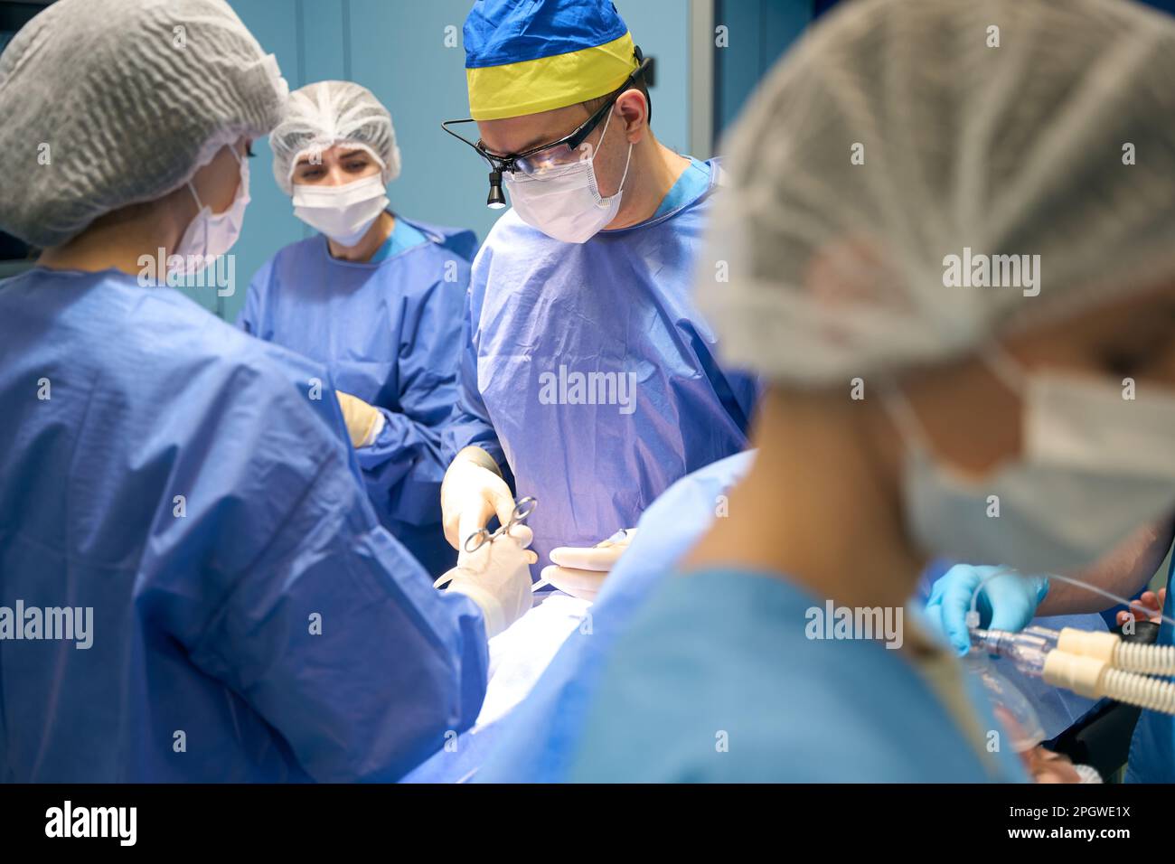 Surgeon in a yellow-blue cap uses a clamp during operation Stock Photo ...