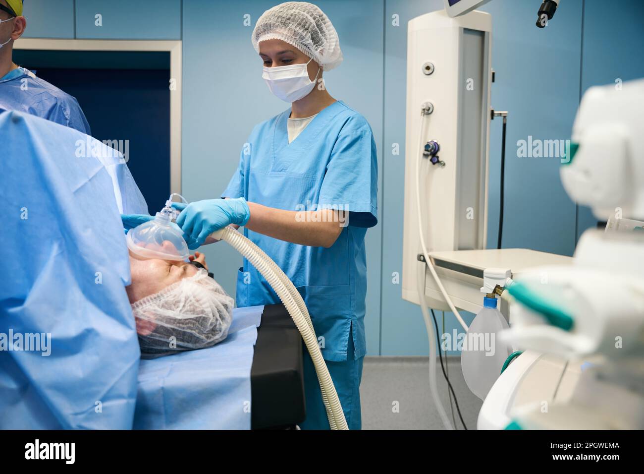Female anesthesiologist holds mask with anesthesia in front patient ...