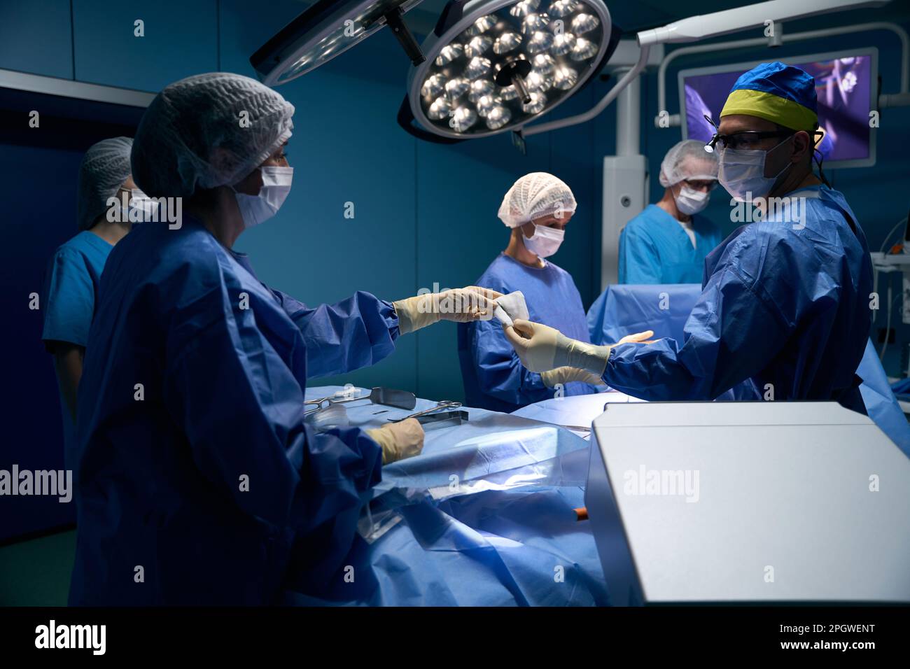 Female assistant gives the surgeon an instrument during the operation ...