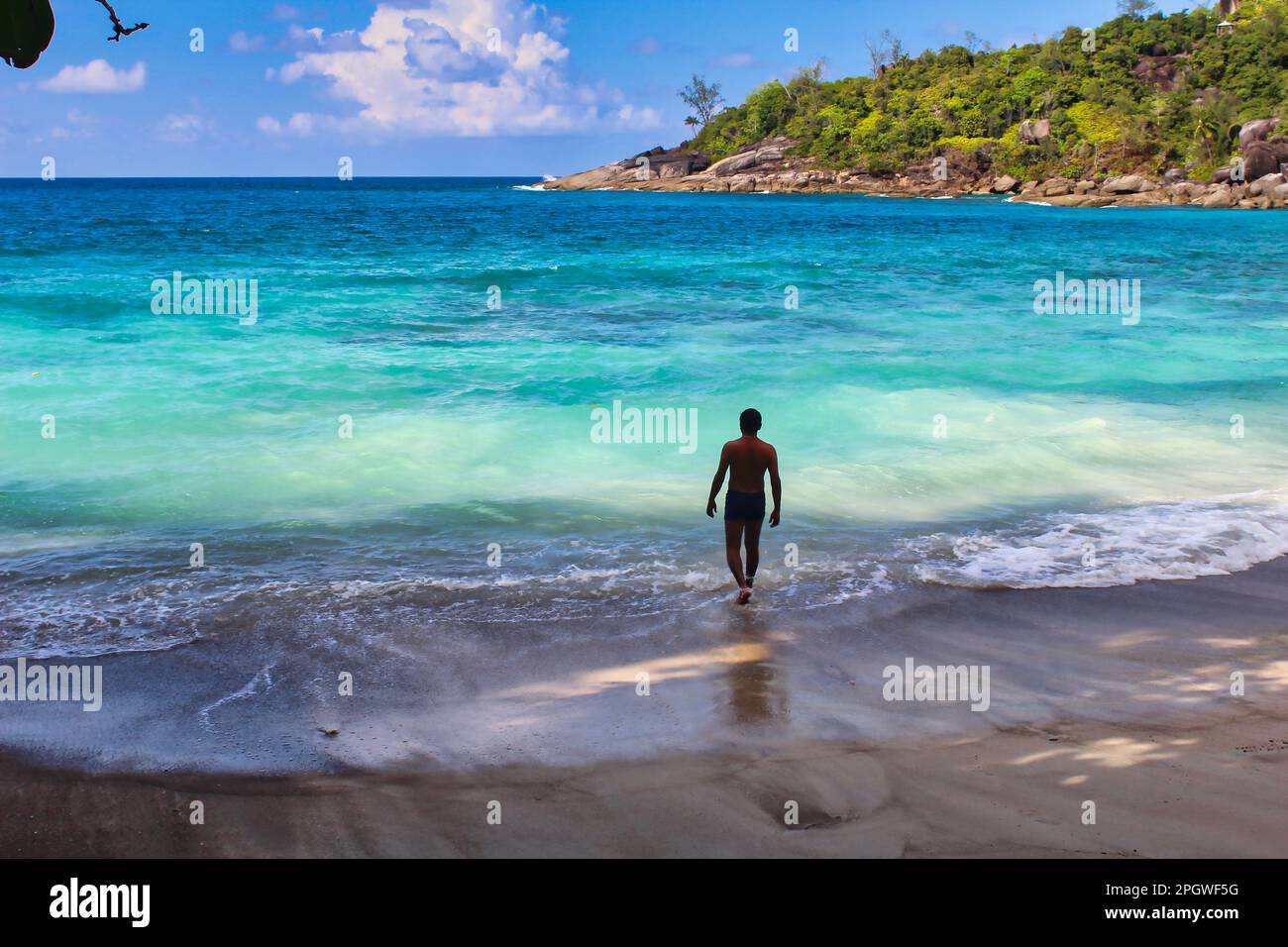 Seychelles, Feb 28th 2015 - A young man enjoys a swim on the secluded ...