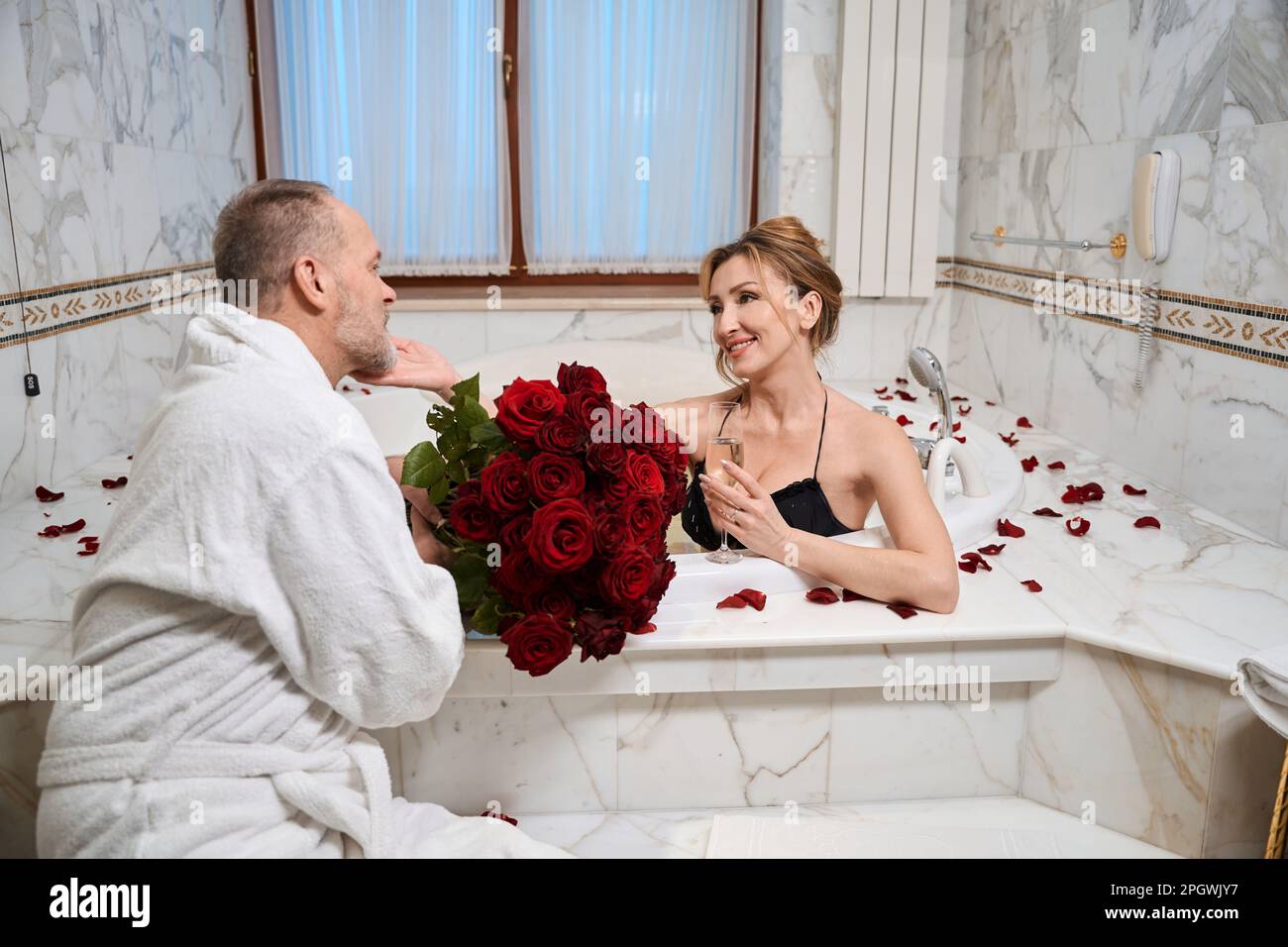 Lady is splashing in a bath with rose petals Stock Photo - Alamy