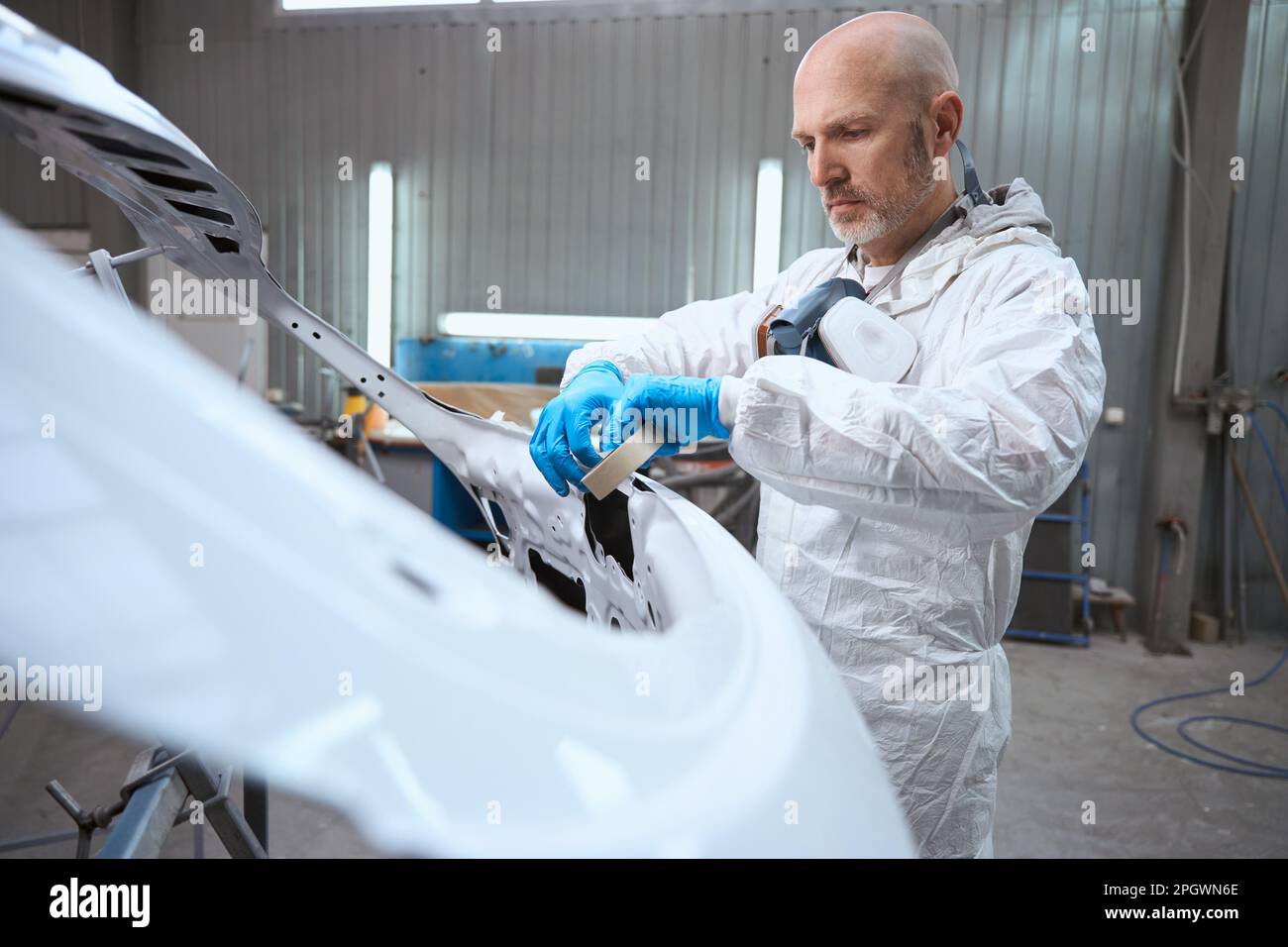Employee of the paint shop prepares a part of the car body for work ...