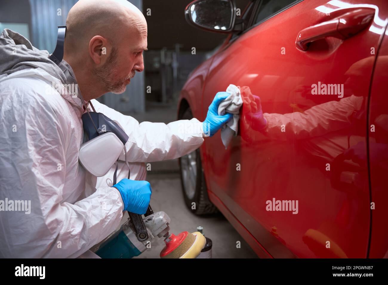 Middle-aged foreman wipes body of red car with soft rag Stock Photo - Alamy