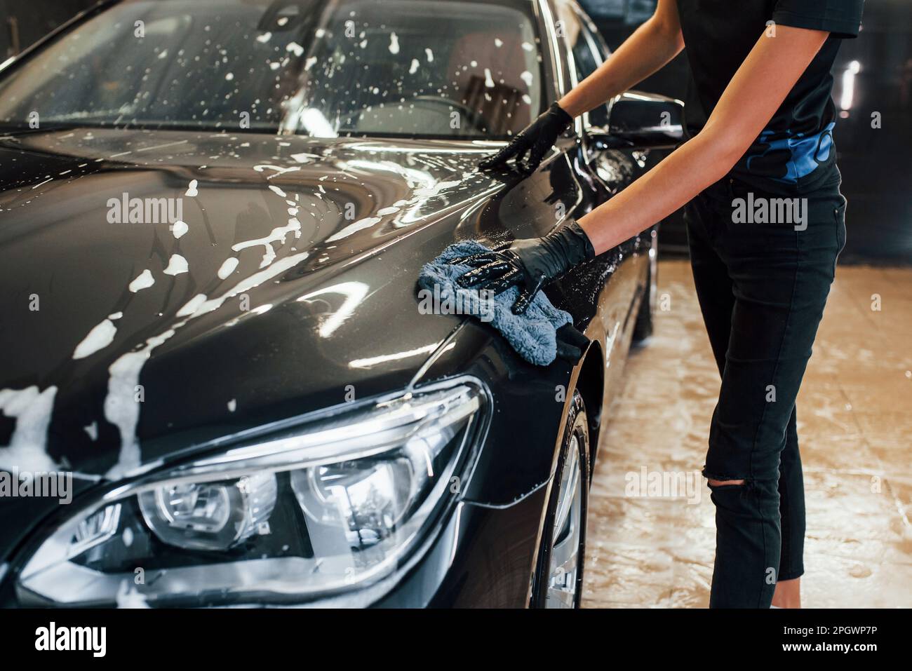 Close up view of vehicle getting wiped. Modern black automobile get ...