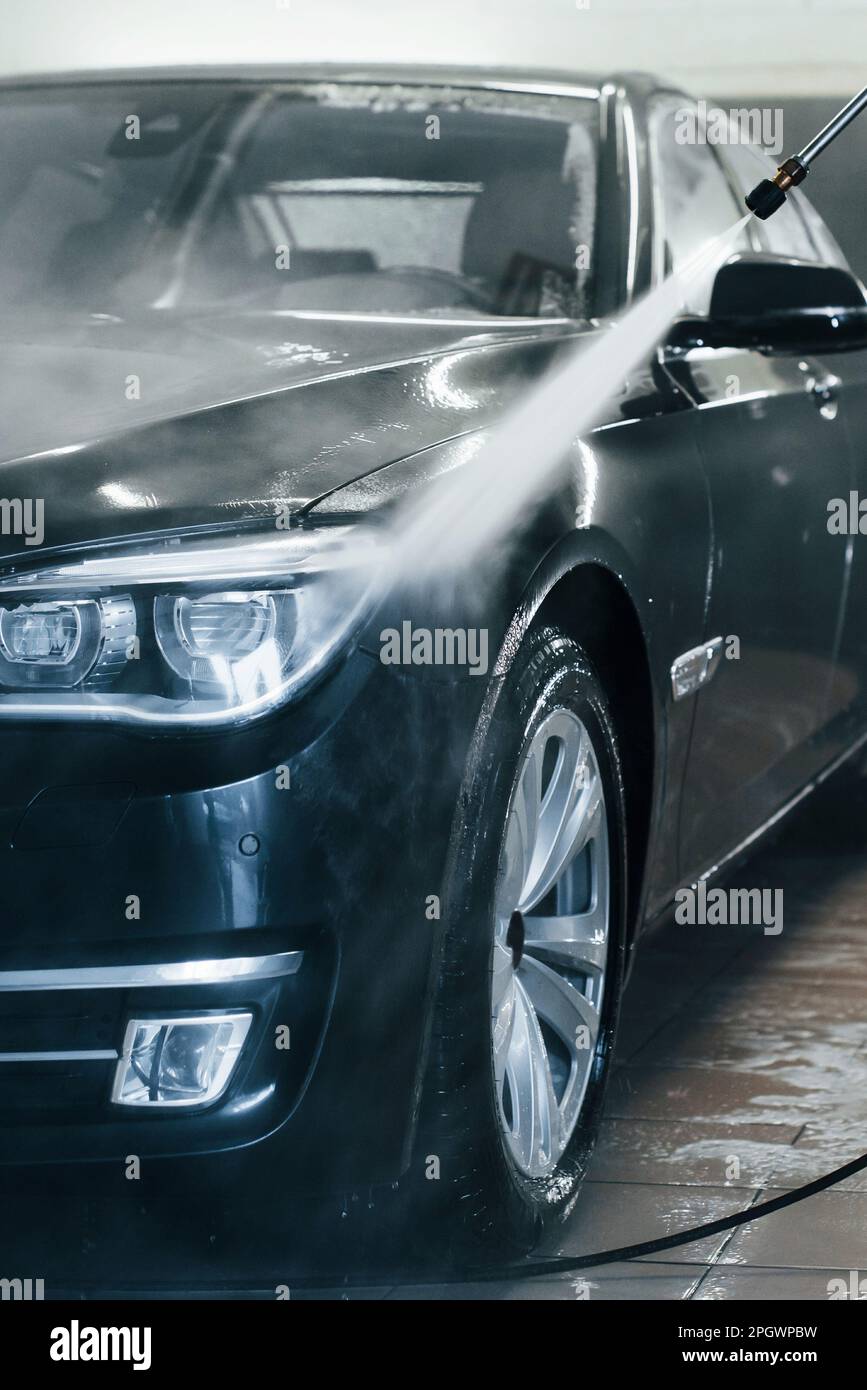 High pressured water. Modern black automobile get cleaned inside of car ...