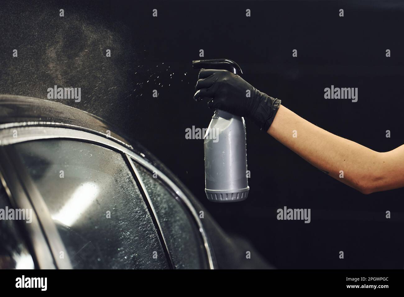 Spraying the vehicle. Modern black automobile get cleaned by woman ...