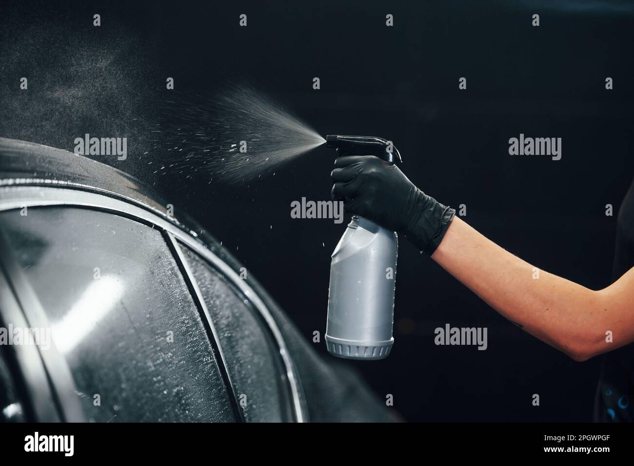 Spraying the vehicle. Modern black automobile get cleaned by woman ...