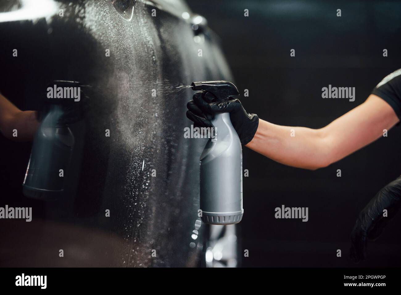 Spraying the vehicle. Modern black automobile get cleaned by woman ...