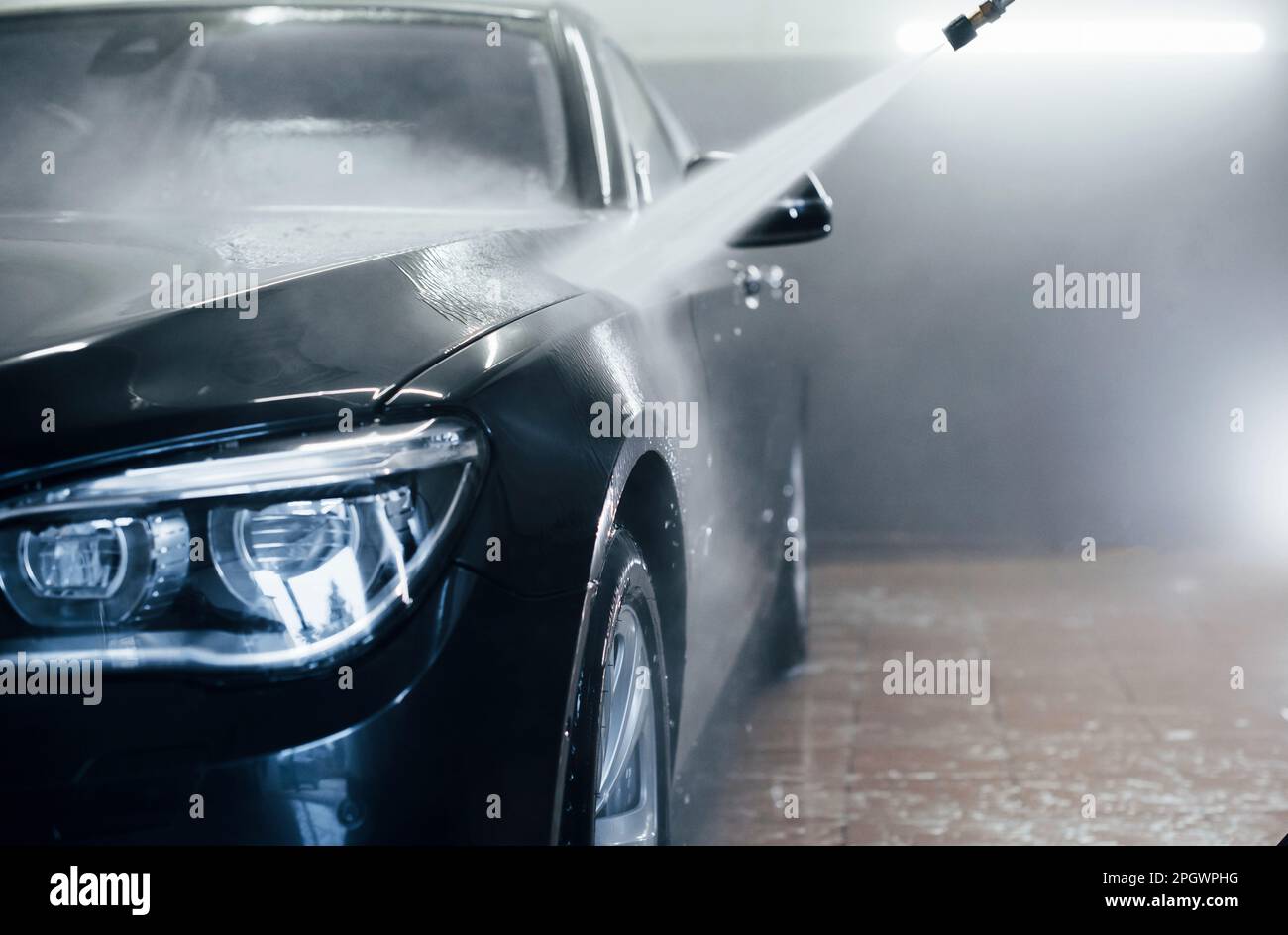 High pressured water. Modern black automobile get cleaned inside of car ...