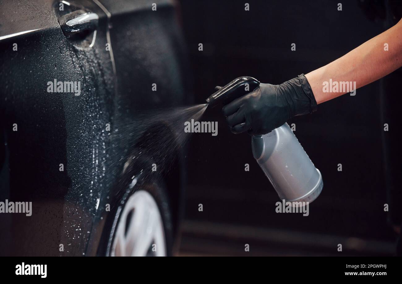 Spraying the vehicle. Modern black automobile get cleaned by woman ...