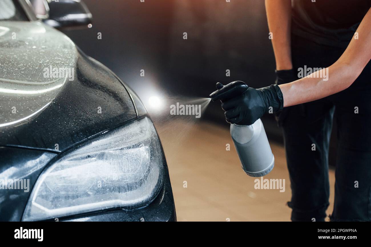 Spraying the vehicle. Modern black automobile get cleaned by woman ...