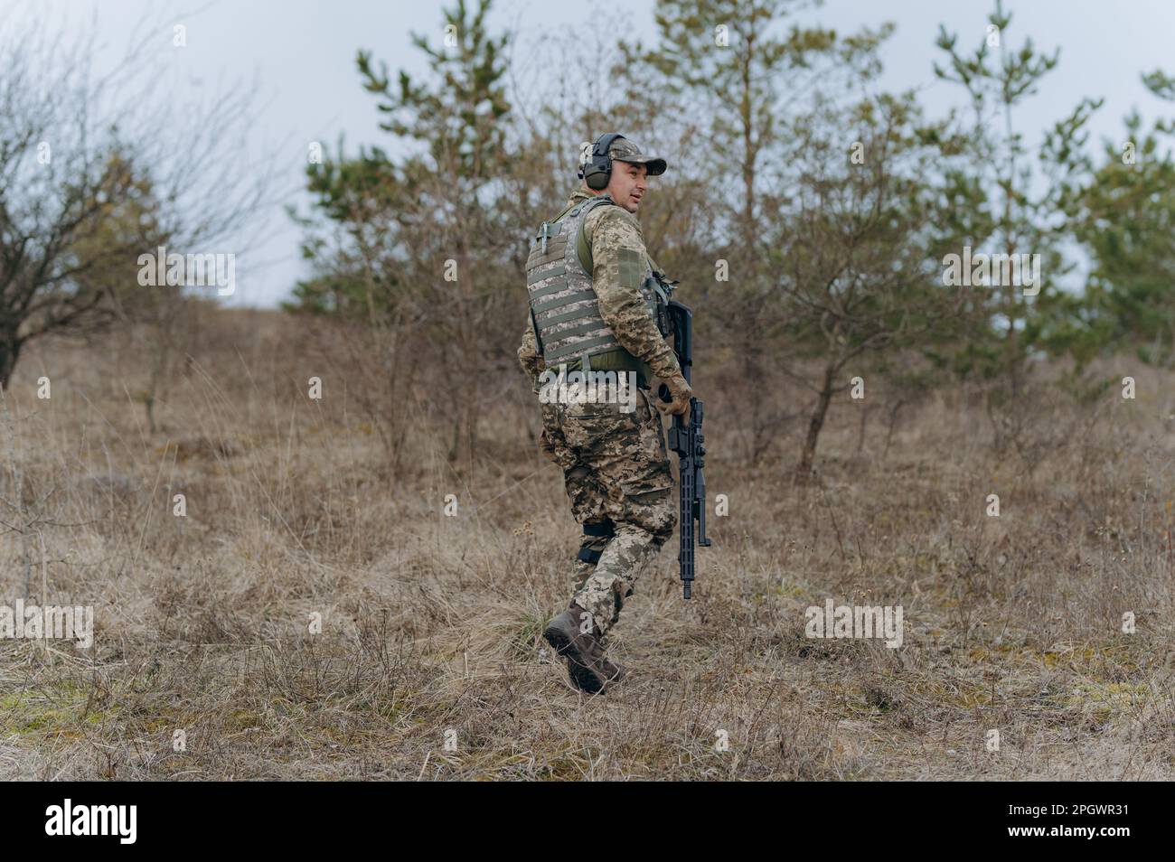 a soldier walks through the forest with a machine gun Stock Photo - Alamy