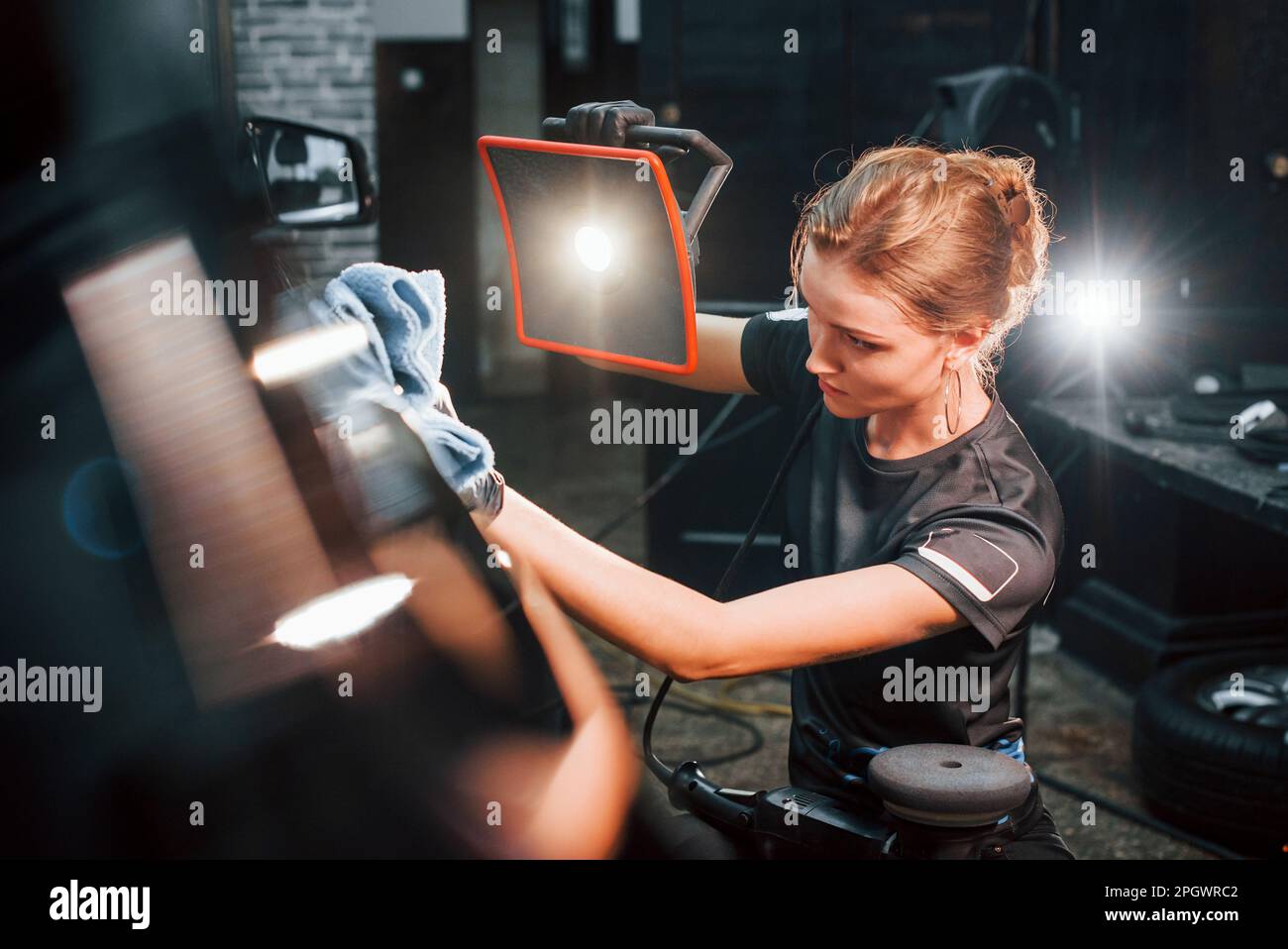 Final polishing. Modern black automobile get cleaned by woman inside of ...