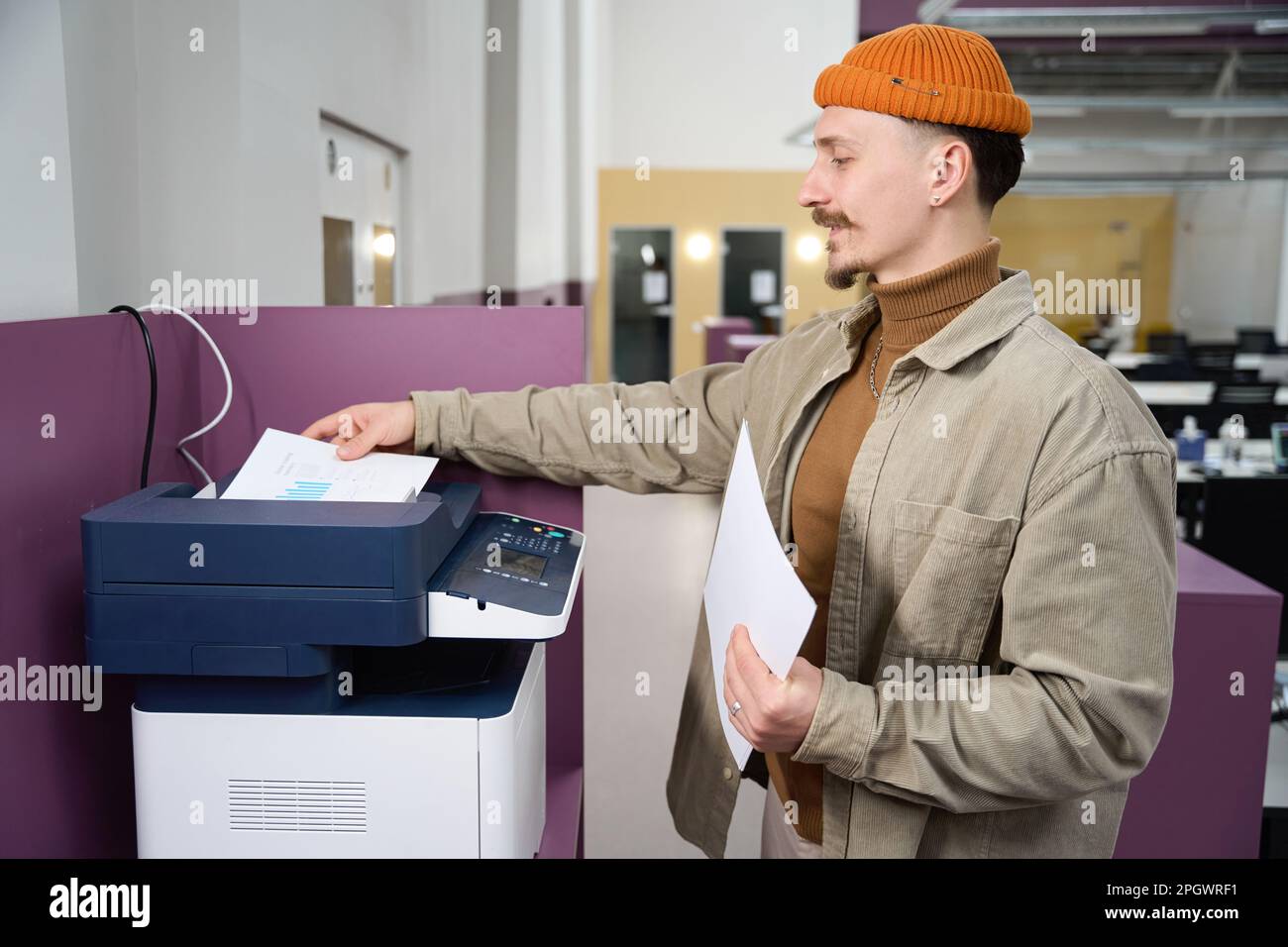 Concentrated young office worker making photocopies on copy machine ...