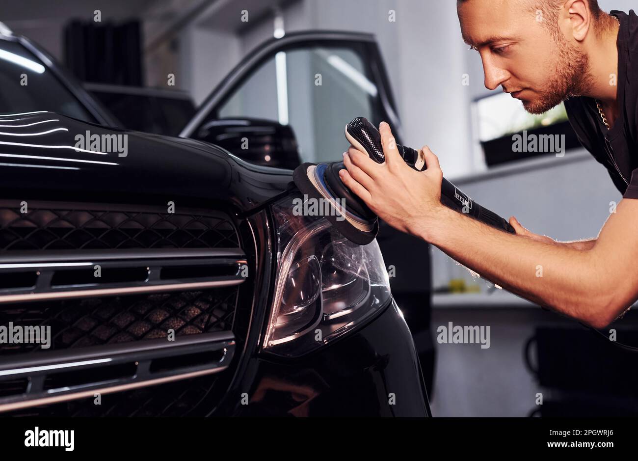 Guy polishing surface of vehicle. Modern black automobile get cleaned ...