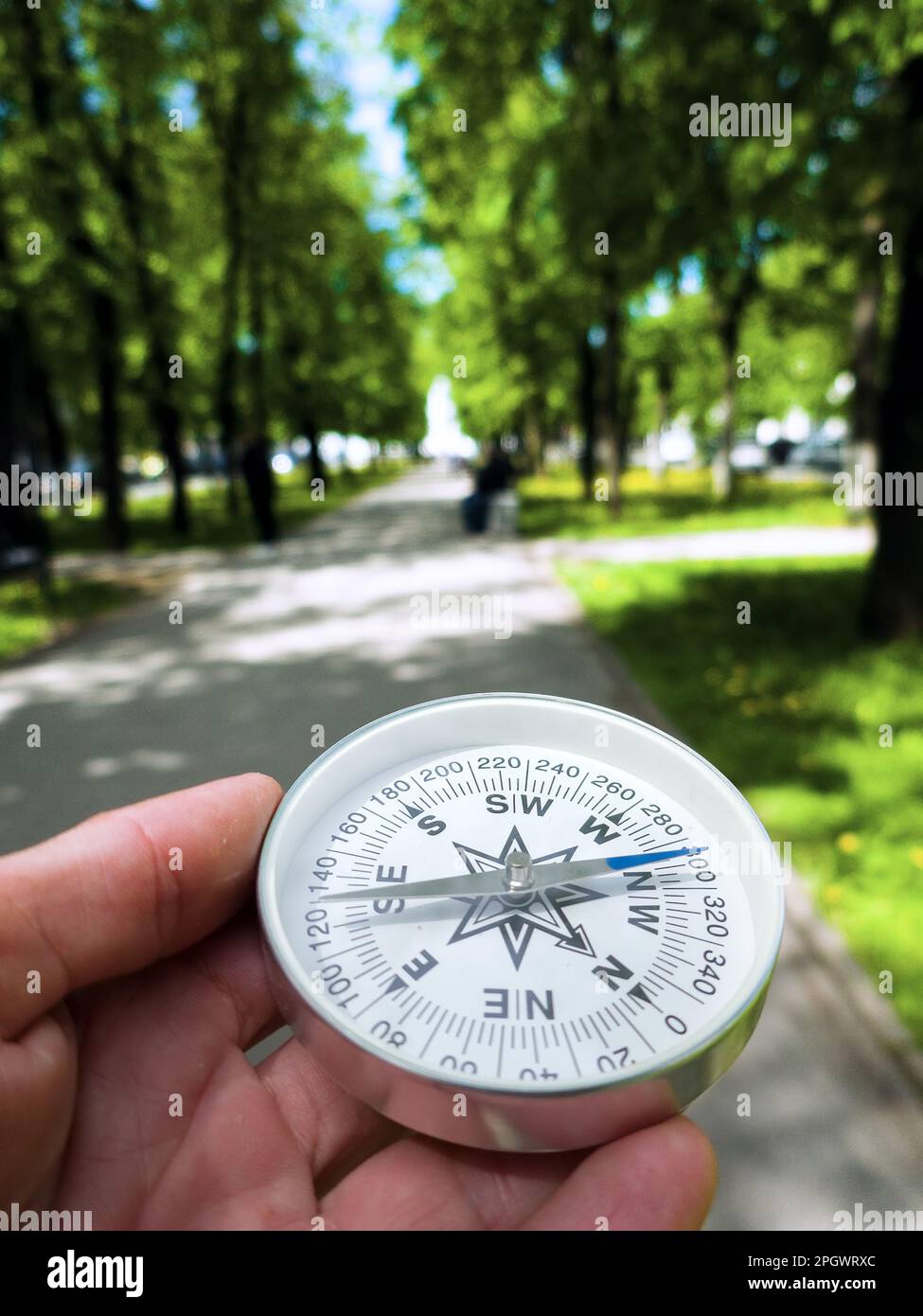 A compass in person's hand in park. Orient yourself in current ...