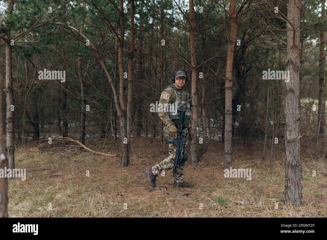 a soldier walks through the forest with a machine gun Stock Photo - Alamy