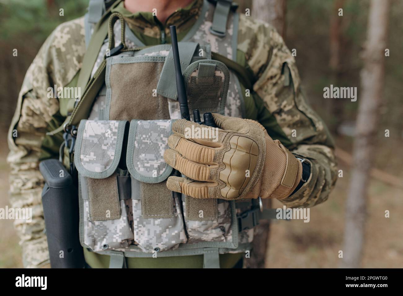 a military man in a camouflage uniform and tactical gloves holds a ...