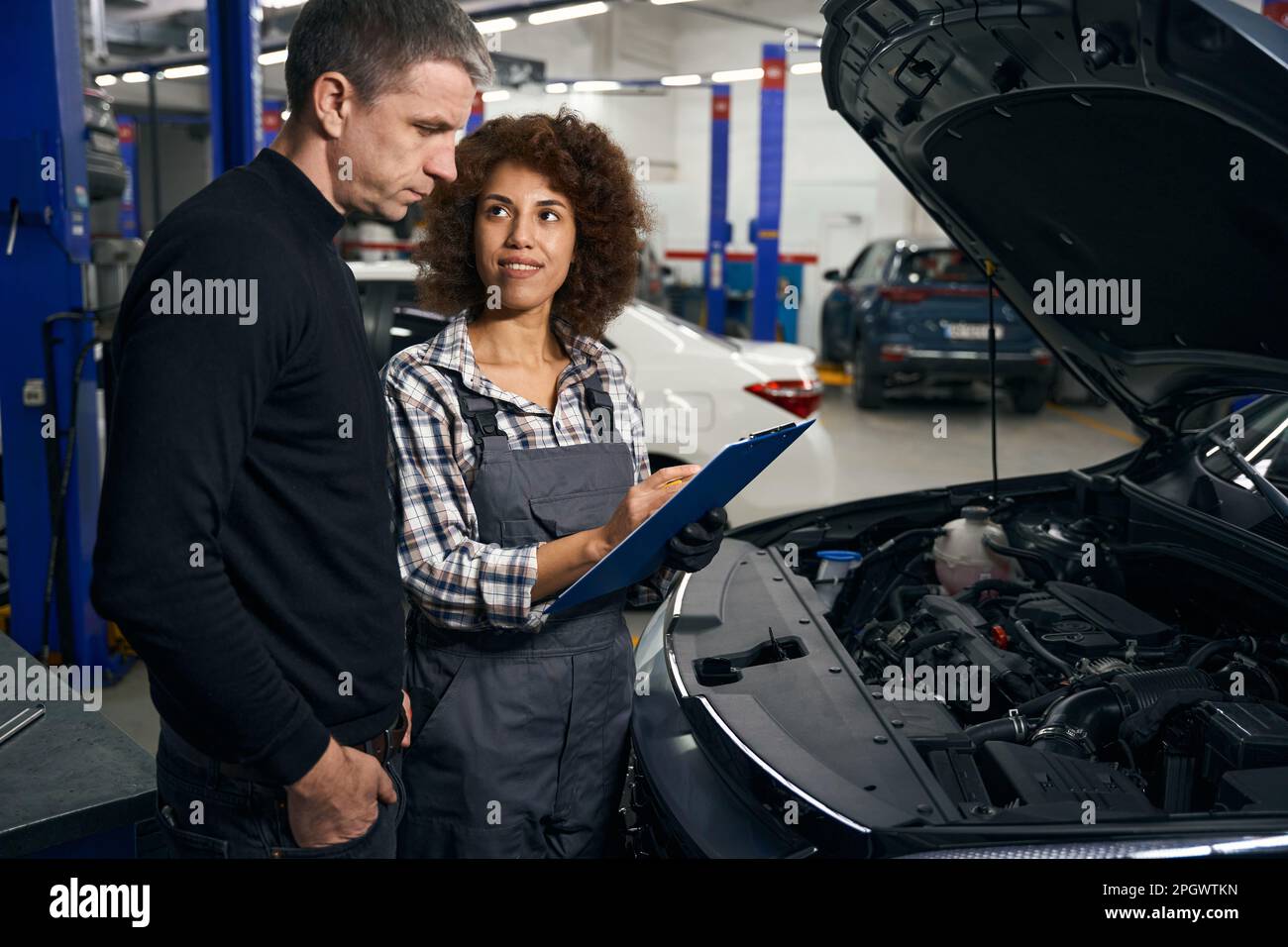 Man in casual clothes and woman in work overalls sign working documents ...