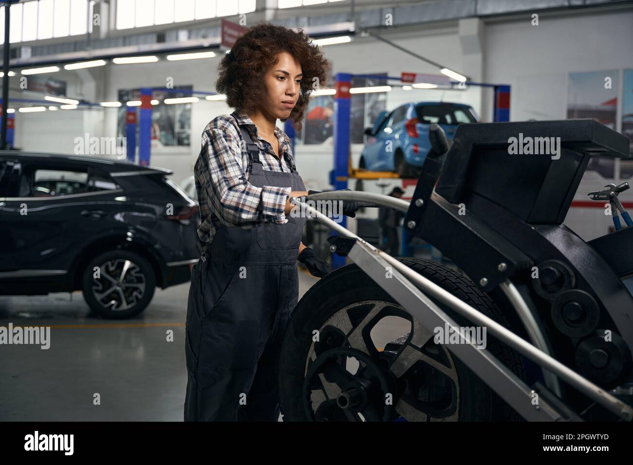 Focused multiracial woman working with wheel in auto repair shop Stock ...