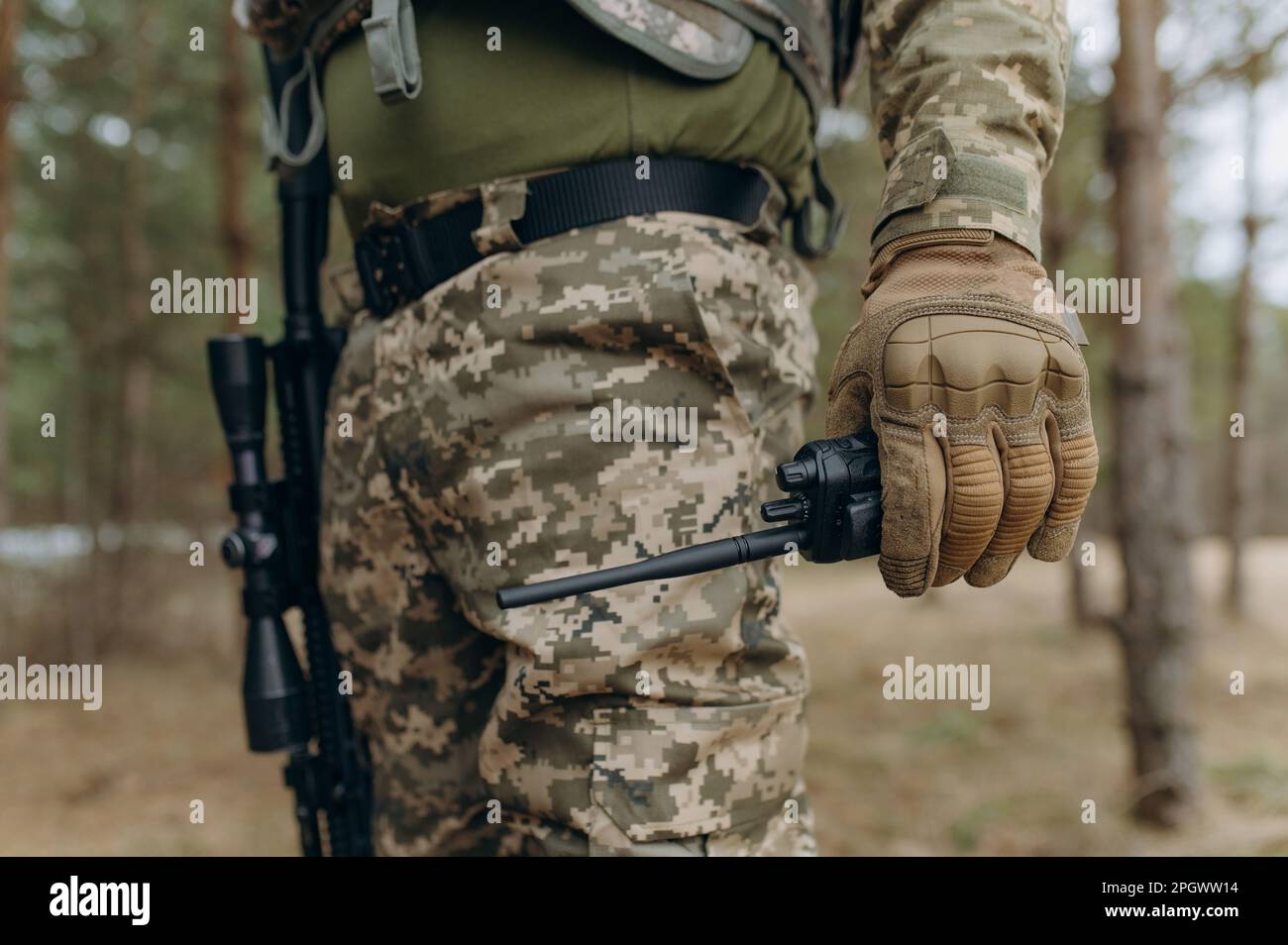 a military man in a camouflage uniform and tactical gloves holds a ...