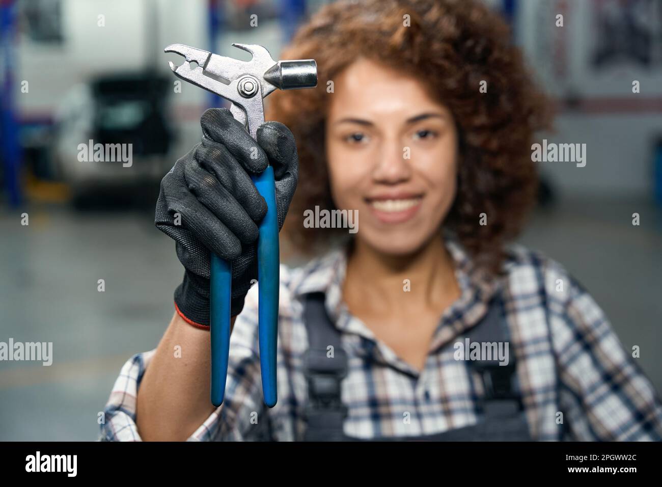 Smiling curly multiracial woman holding adjustable wrench Stock Photo ...