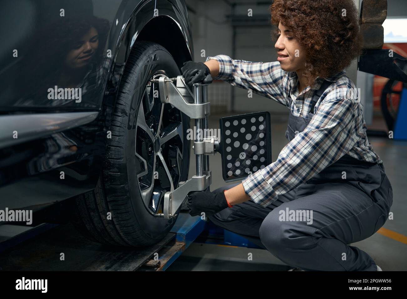 Woman auto mechanic repairing a wheel in a car workshop Stock Photo - Alamy