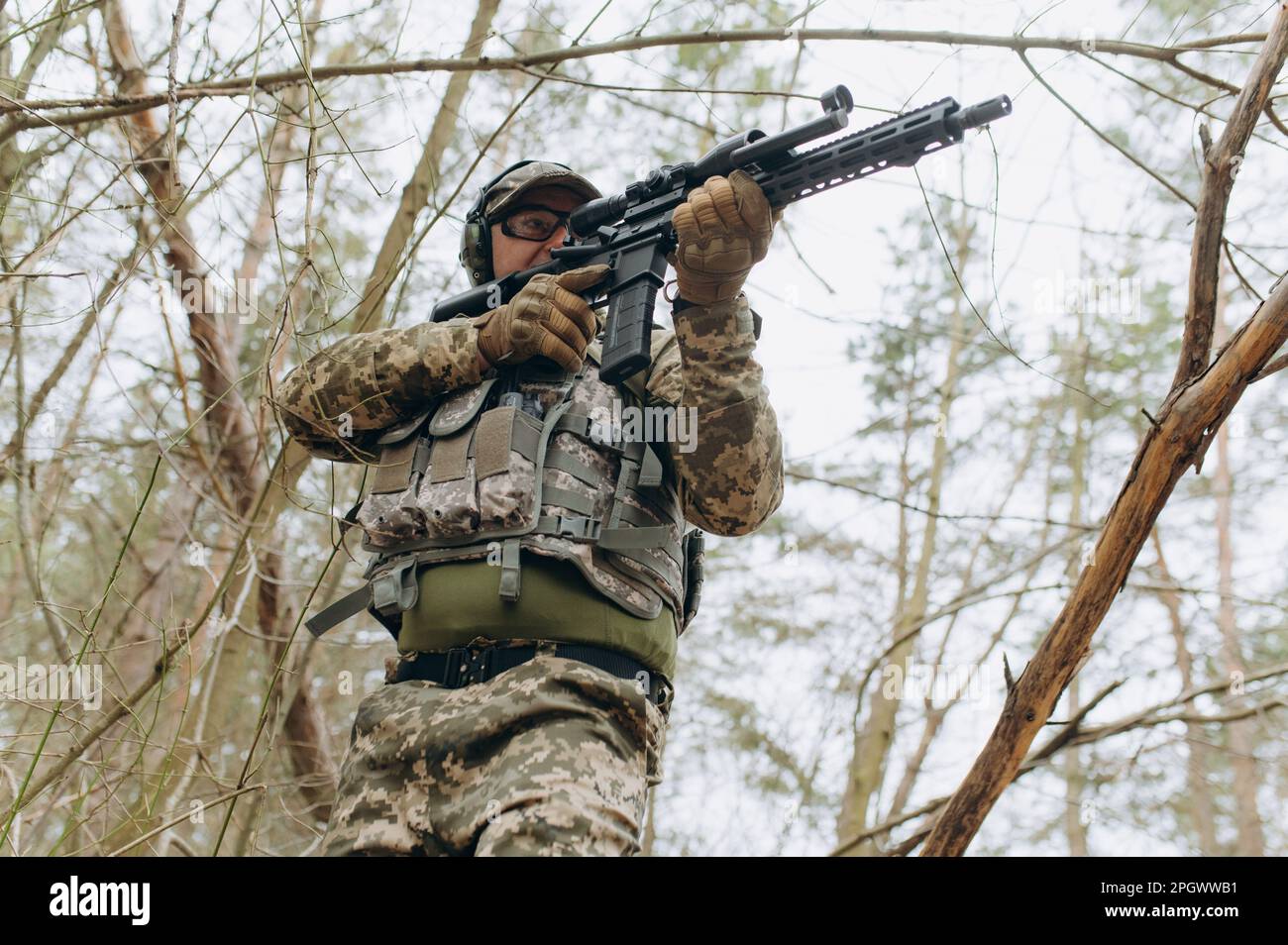 military man in camouflage uniform on tree branches, in an ambush with ...