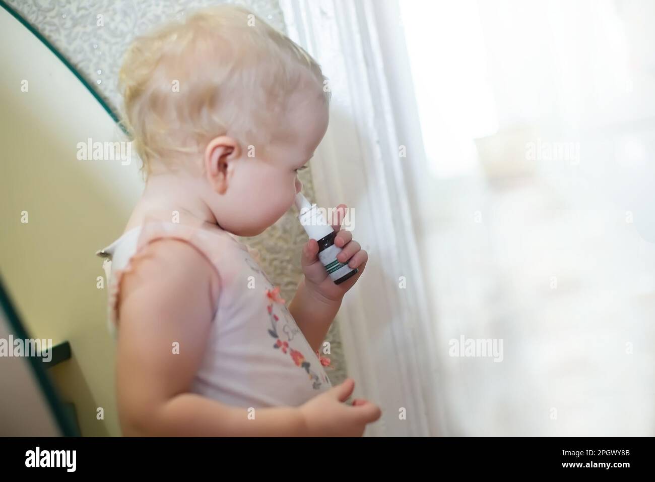 little girl buries nose with drops from medicinal bottle with dispenser ...
