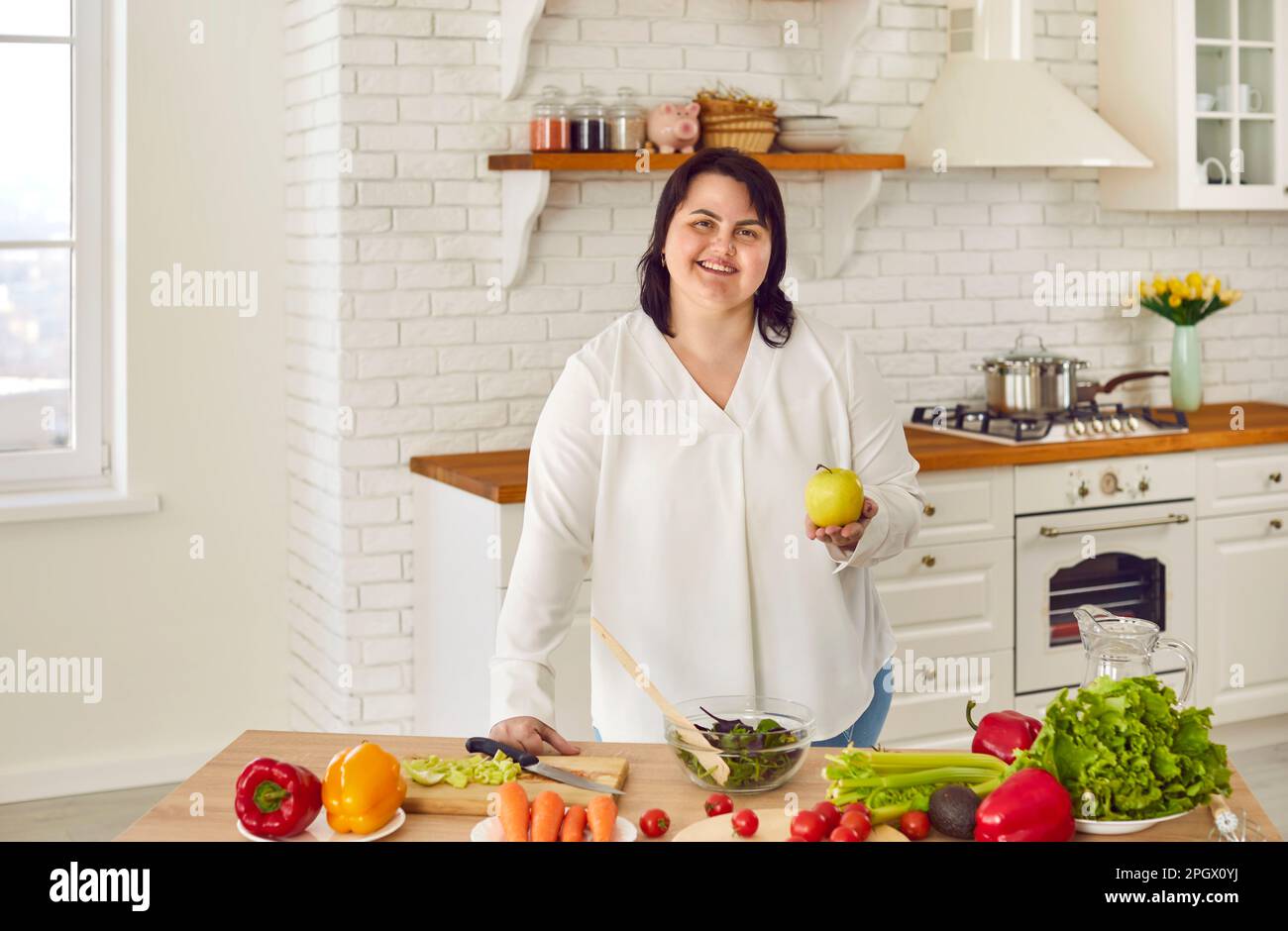 Overweight young woman cooking healthy food in modern kitchen Stock ...